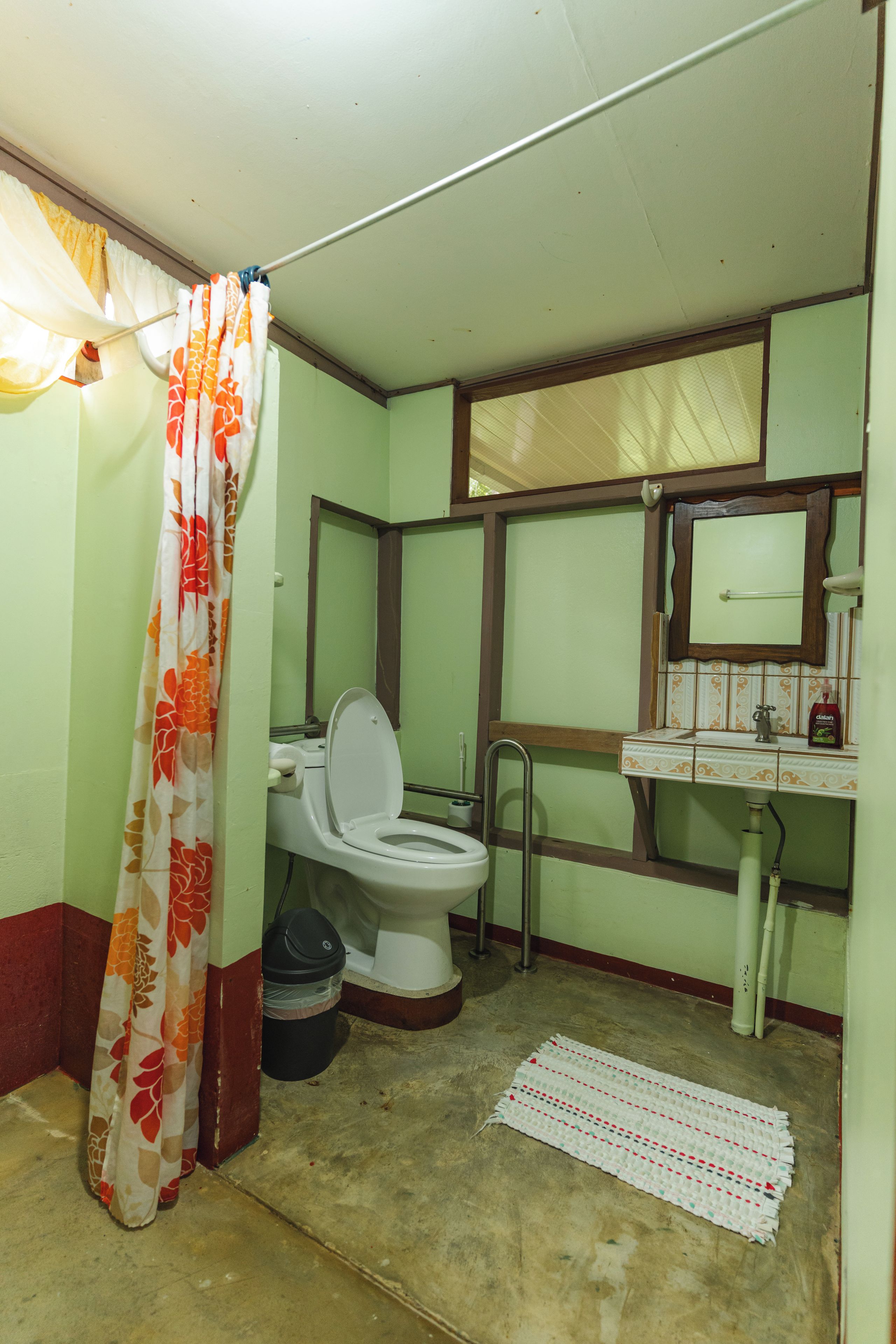 Casa de banho pequena e funcional, com sanita, lavatório e cortina de chuveiro.