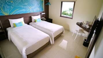 Quarto de hotel com duas camas, uma escrivaninha, uma cadeira, uma televisão e uma janela.