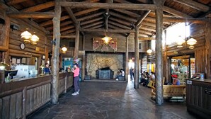 Um interior rústico com lareira de pedra, vigas de madeira e um espaço de bar.