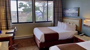 Quarto de hotel com uma cama grande, uma escrivaninha e vista para um cânion pela janela.