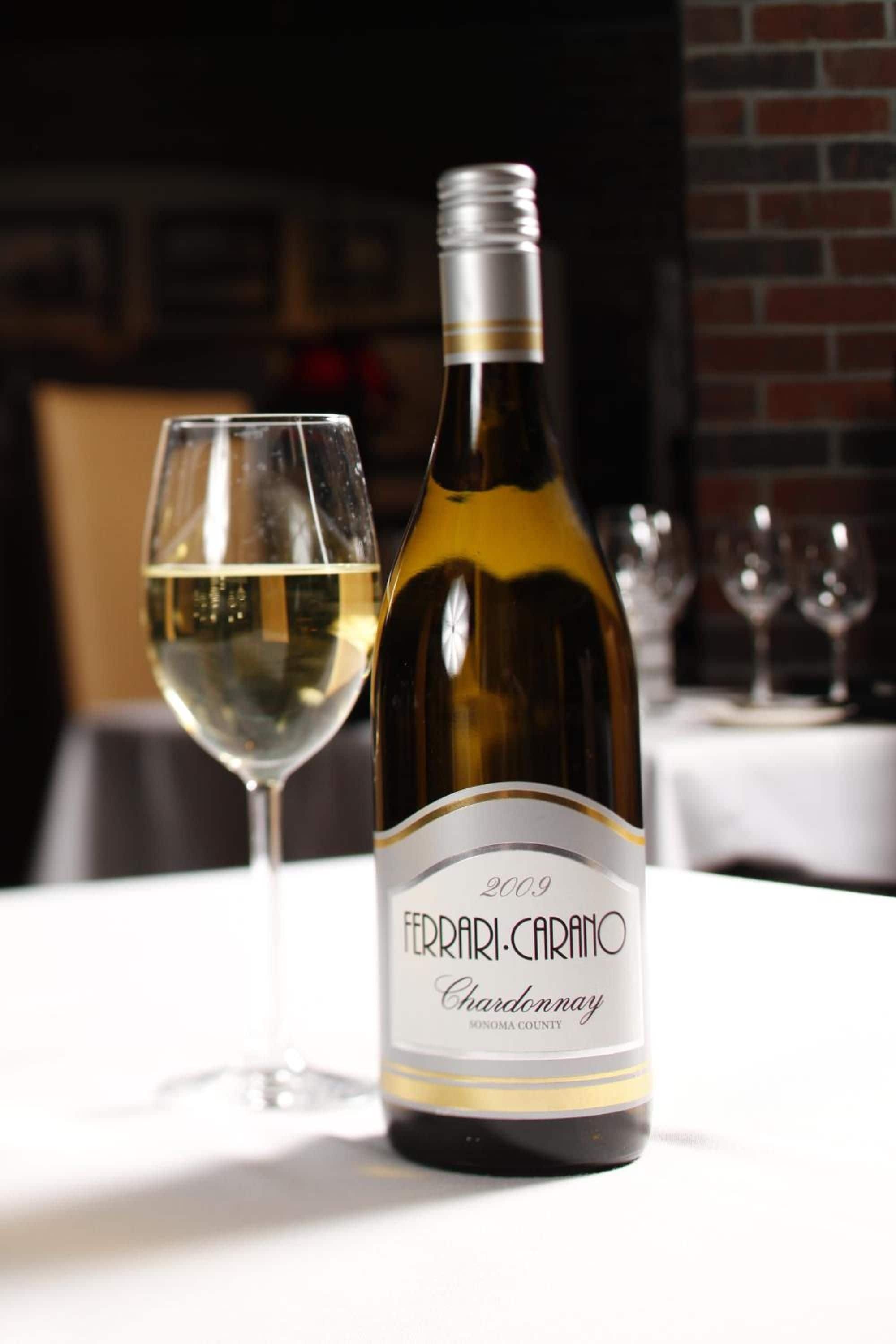 Uma garrafa de Chardonnay Ferrari-Carano de 2009 sobre uma mesa, com um copo de vinho branco.