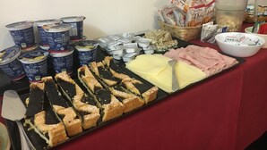 Mesa de buffet com diversos alimentos, incluindo iogurte, queijo e doces.