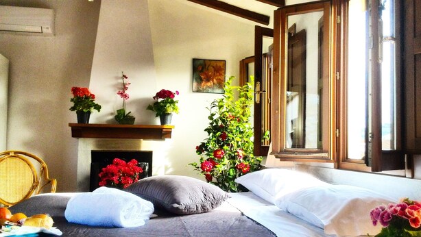 Quarto com cama, almofadas, uma cadeira e lareira.
