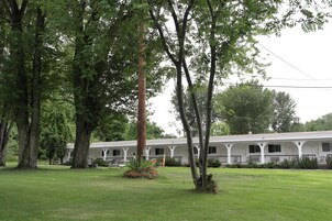 Fileira de edifícios tipo motel, com galeria coberta e gramado.