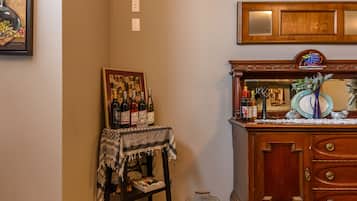 Quarto com um armário de madeira, uma mesa pequena com um tecido, uma planta em vaso e um tapete estampado.