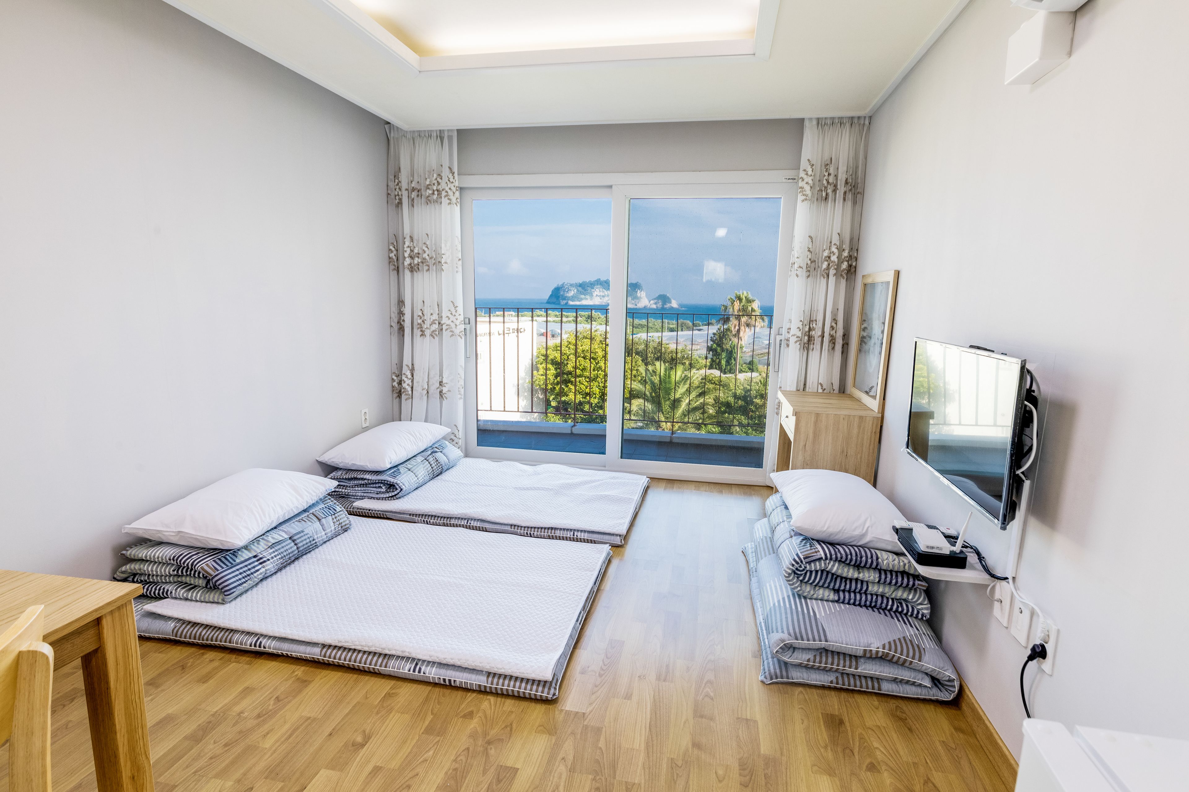 Quarto de hotel com duas camas, televisão e varanda com vista para o mar.
