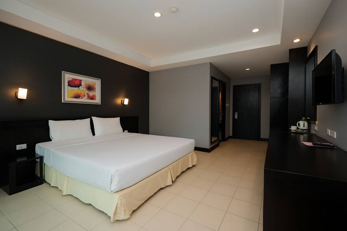 Quarto de hotel moderno com cama grande, mesas de cabeceira, televisão de tela plana e um quadro na parede.