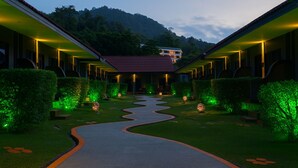 Hotel com um pátio central, rodeado por edifícios com grades iluminadas, e uma montanha ao fundo.