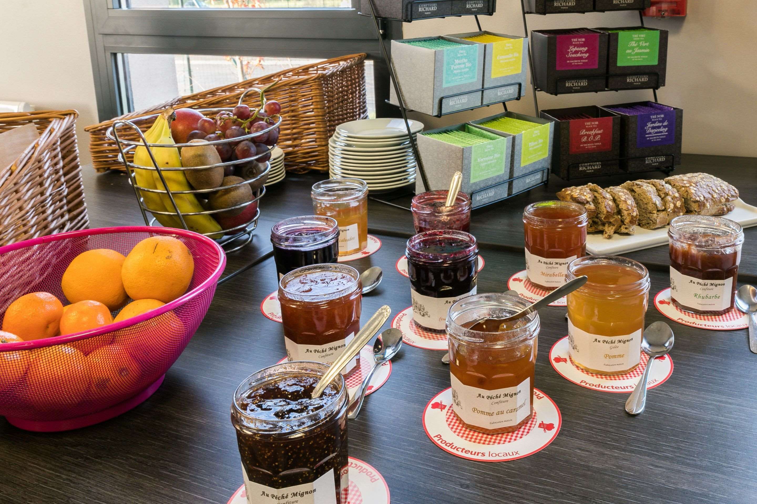 Uma mesa de café da manhã com diversas geleias, frutas e doces.
