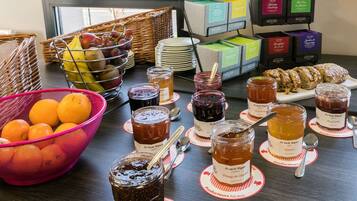 Uma mesa de café da manhã com diversas geleias, frutas e doces.