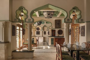 Interior espaçoso com teto alto, arcos ornamentados e um lustre central.