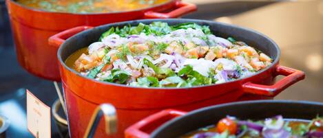 Três panelas vermelhas com comida, uma com salada e as outras com sopa.