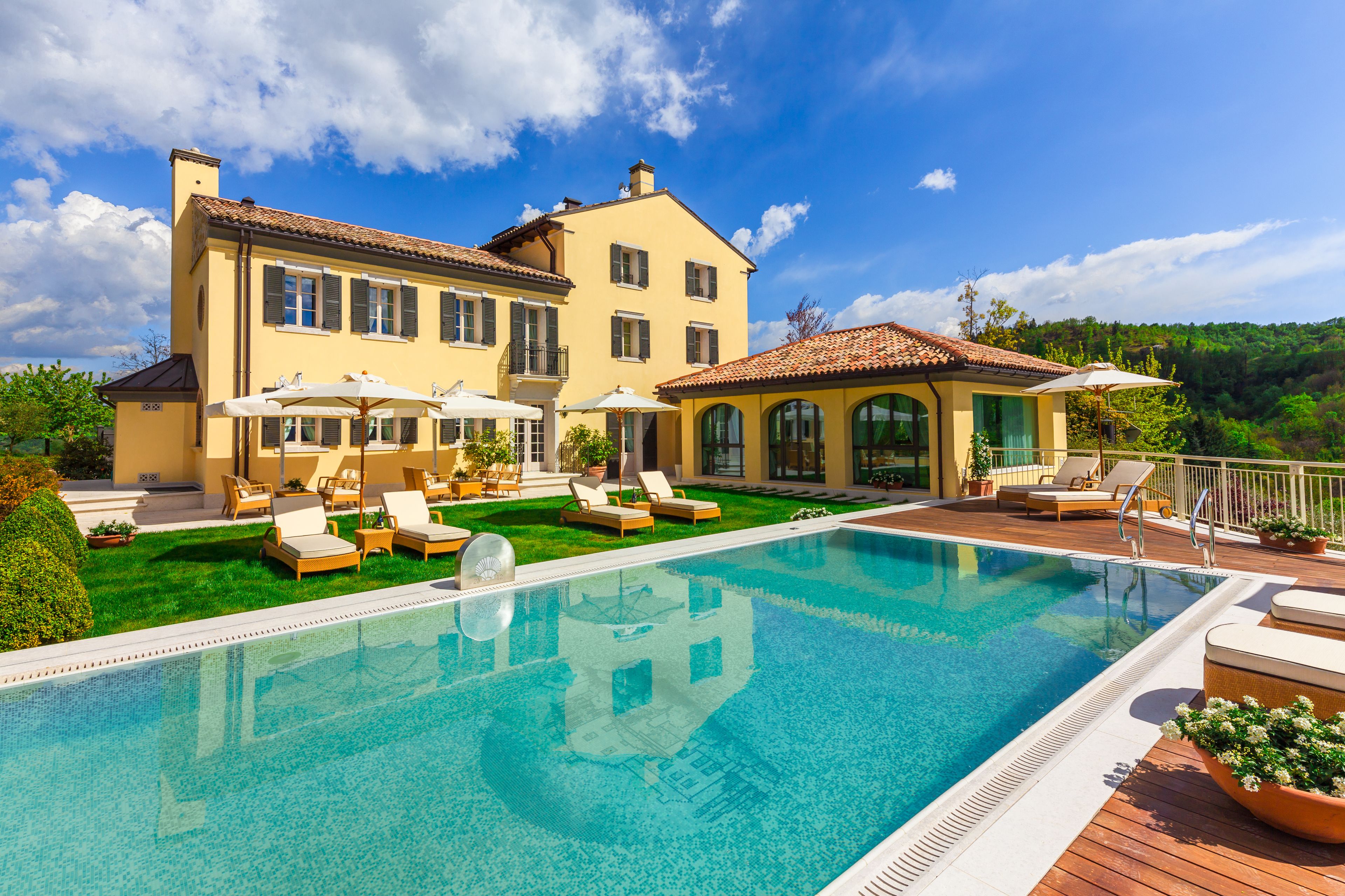 Uma casa grande com piscina, móveis de exterior e um gramado bem cuidado.