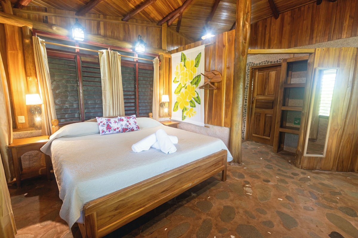 Um quarto de madeira com uma cama, um relógio de parede e um quadro.