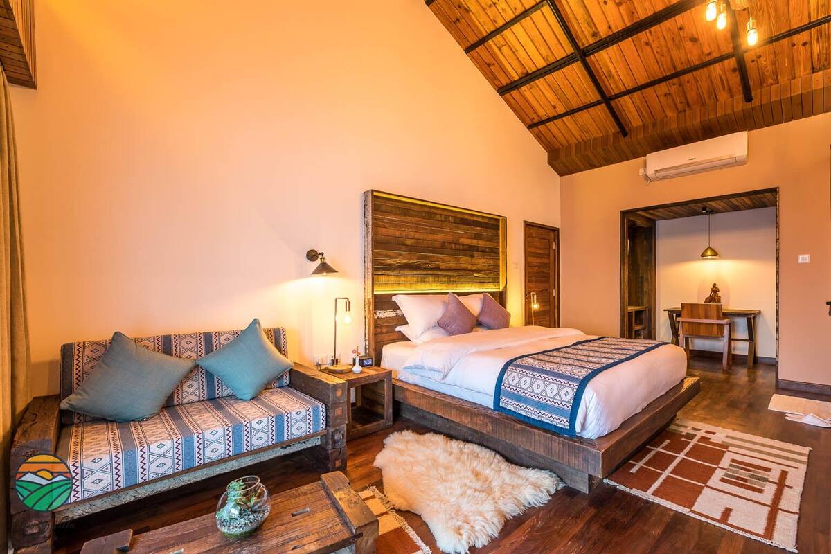 Um quarto aconchegante com uma cama, um sofá, uma mesinha e um tapete.