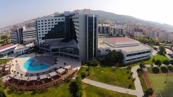 Um edifício moderno com um pátio central, piscina e vegetação ao redor.