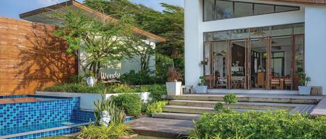 Uma casa moderna com piscina, deck de madeira e jardim.