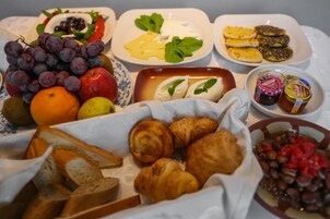 Um buffet de café da manhã com diversas frutas, pães e acompanhamentos.