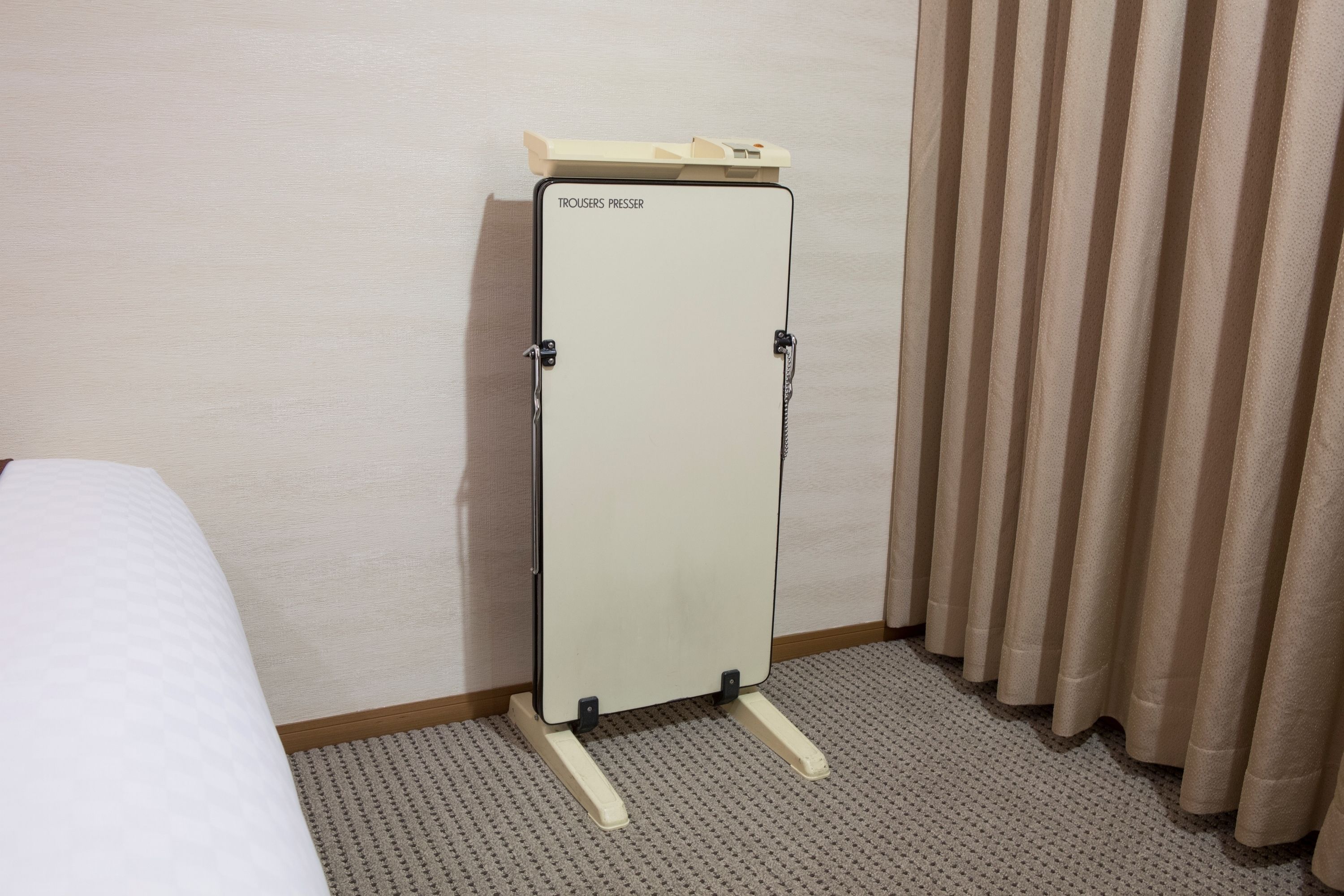 Quarto com uma cama, um guarda-roupa branco e uma cortina.