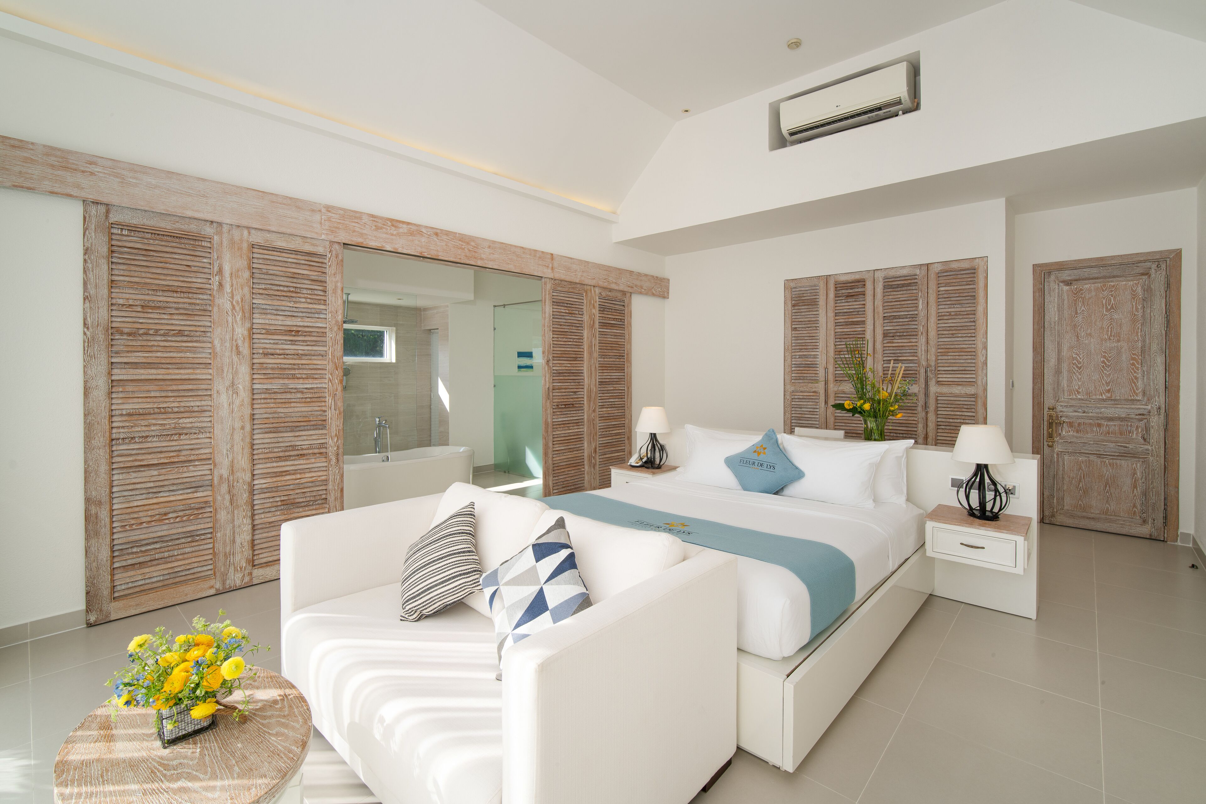 Um quarto moderno com uma cama grande, um sofá e uma pequena mesa com flores.