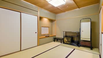 Um quarto japonês tradicional com tatames, portas corrediças, um pequeno banco e uma estante com espelho.