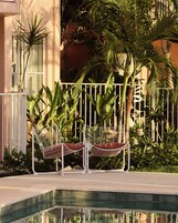 Área de piscina com duas redes e uma cerca branca.