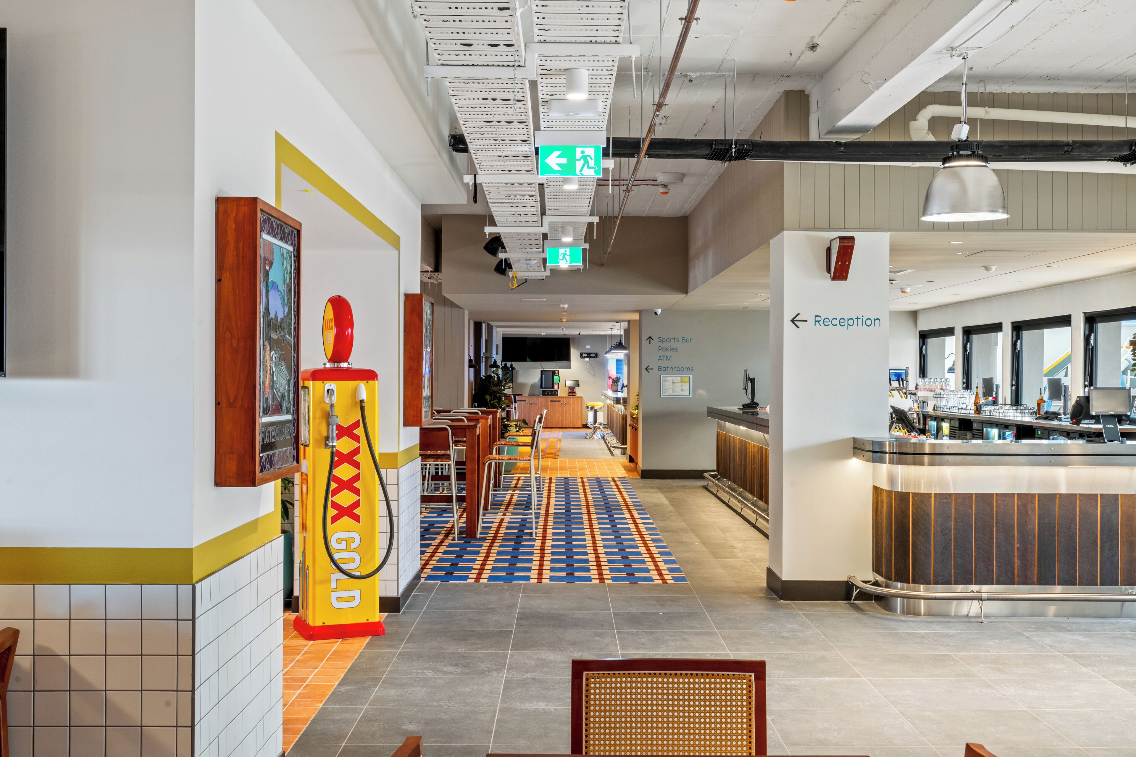 Um saguão de hotel com balcão de recepção, bar esportivo e caixa eletrônico.