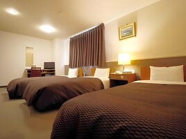 Quarto de hotel com duas camas, televisão, secretária e abajur.