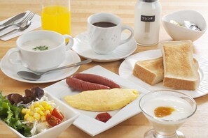 Uma mesa de café da manhã com uma xícara de café, uma tigela de sopa, torradas, um prato de linguiça, uma salada e um copo de leite.