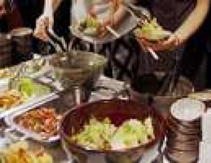Buffet com diversos pratos e uma tigela de frutas.