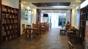 Uma biblioteca com estantes de madeira, mesas e cadeiras dispostas para leitura e estudo.