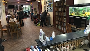 Uma biblioteca com estantes, uma televisão e um aquário.