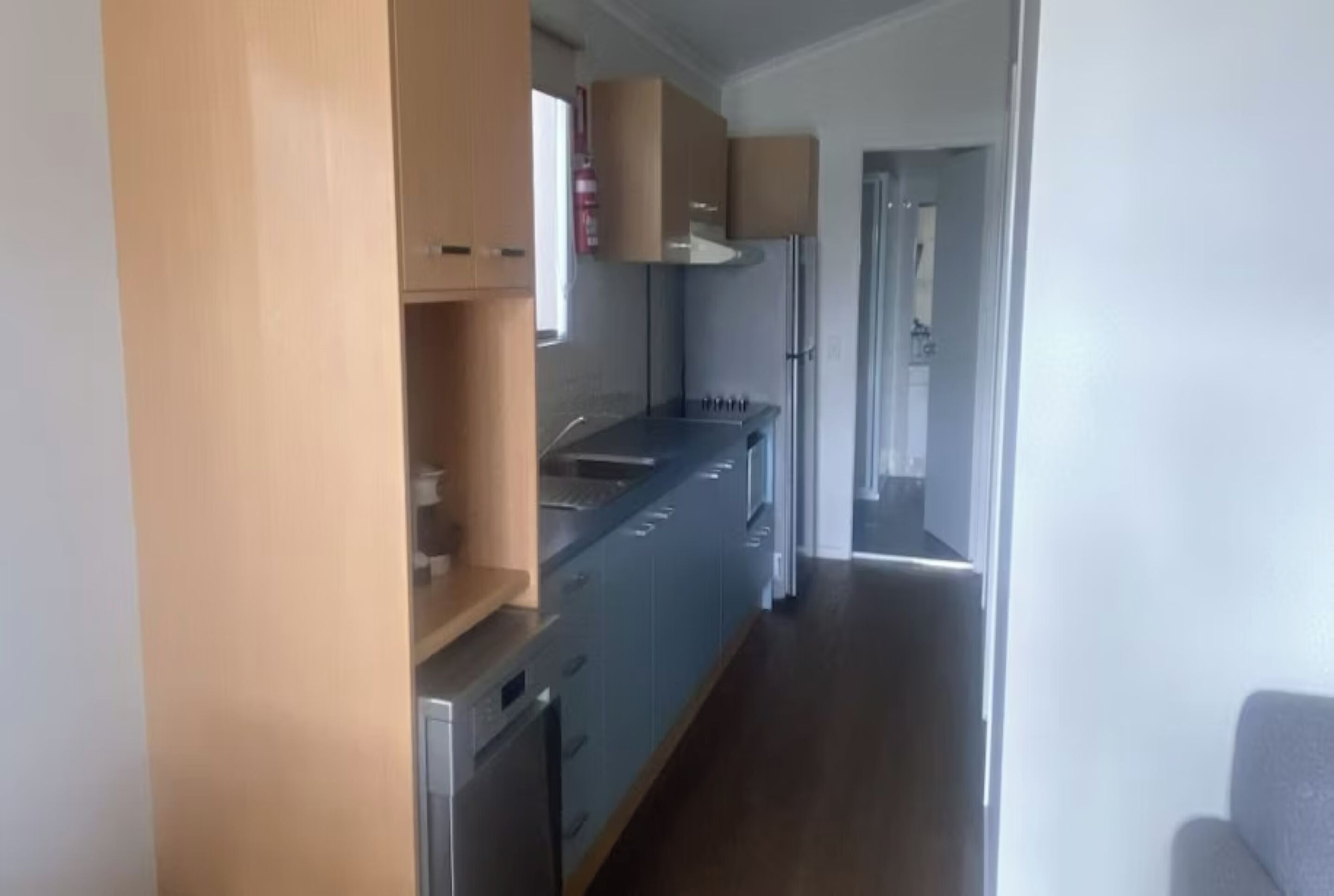 Cozinha moderna com armários de madeira, pia de aço inoxidável e forno embutido.