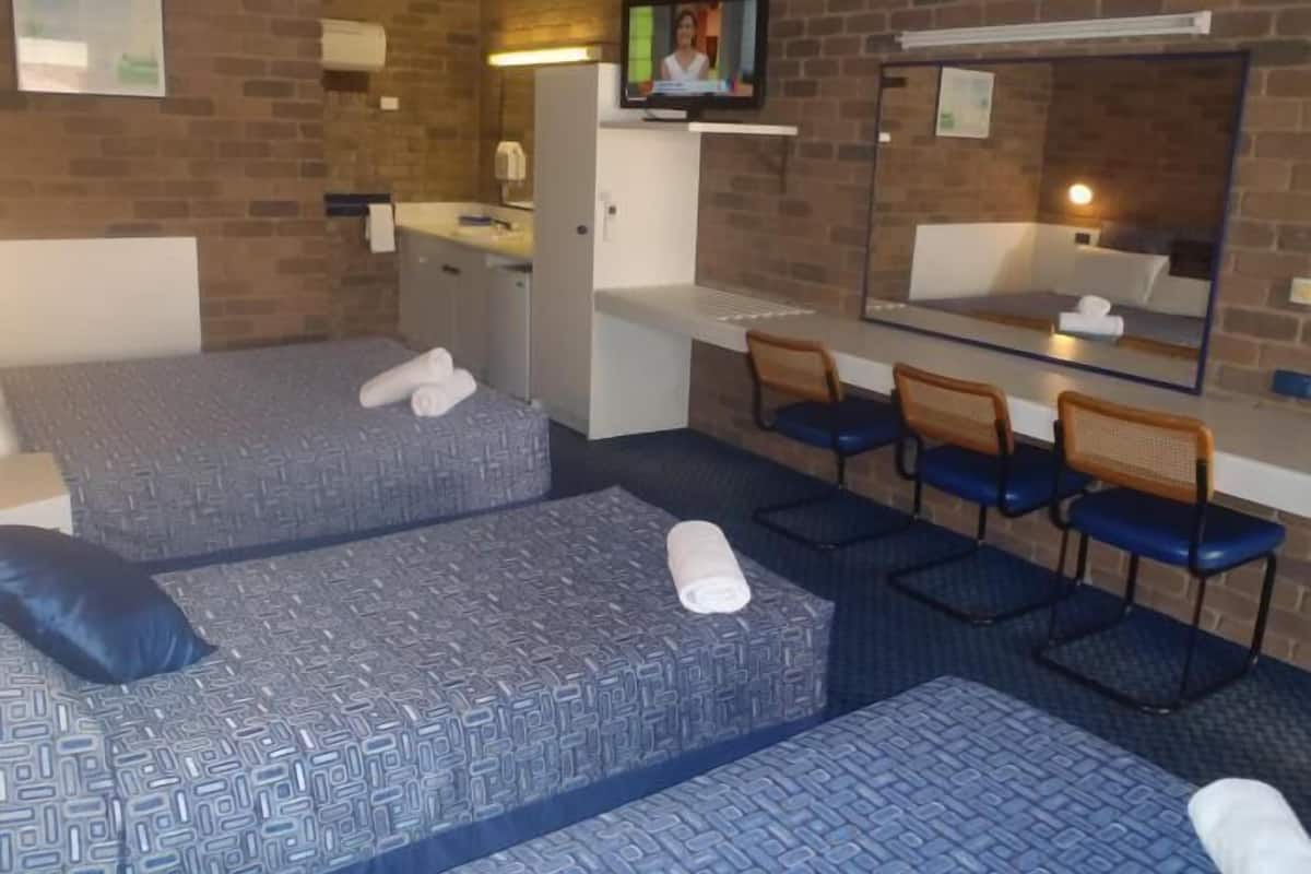 Quarto de hotel com duas camas, uma escrivaninha, uma cadeira, um espelho e uma televisão.
