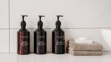 Três frascos de produtos de cuidados para a pele Eloura Australia e uma toalha dobrada em uma bancada de banheiro.
