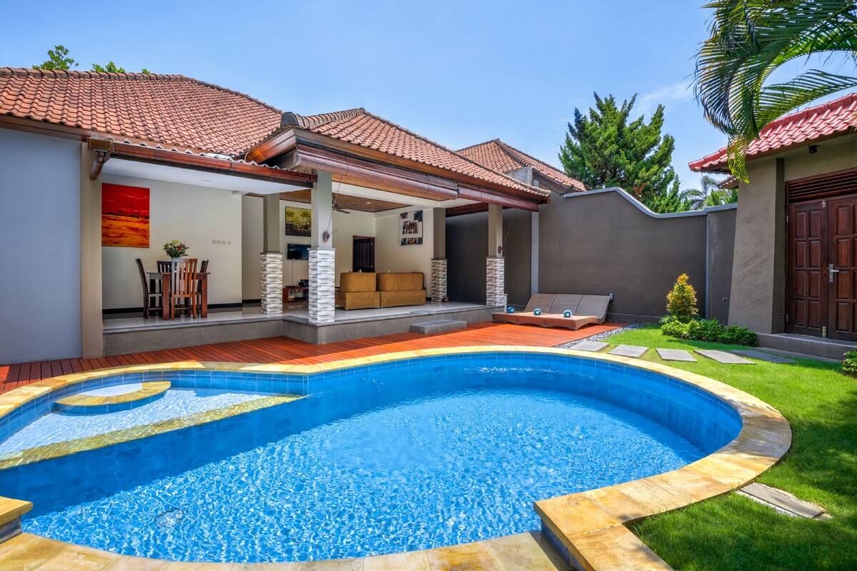 Um imóvel residencial com piscina, varanda coberta e gramado bem cuidado.