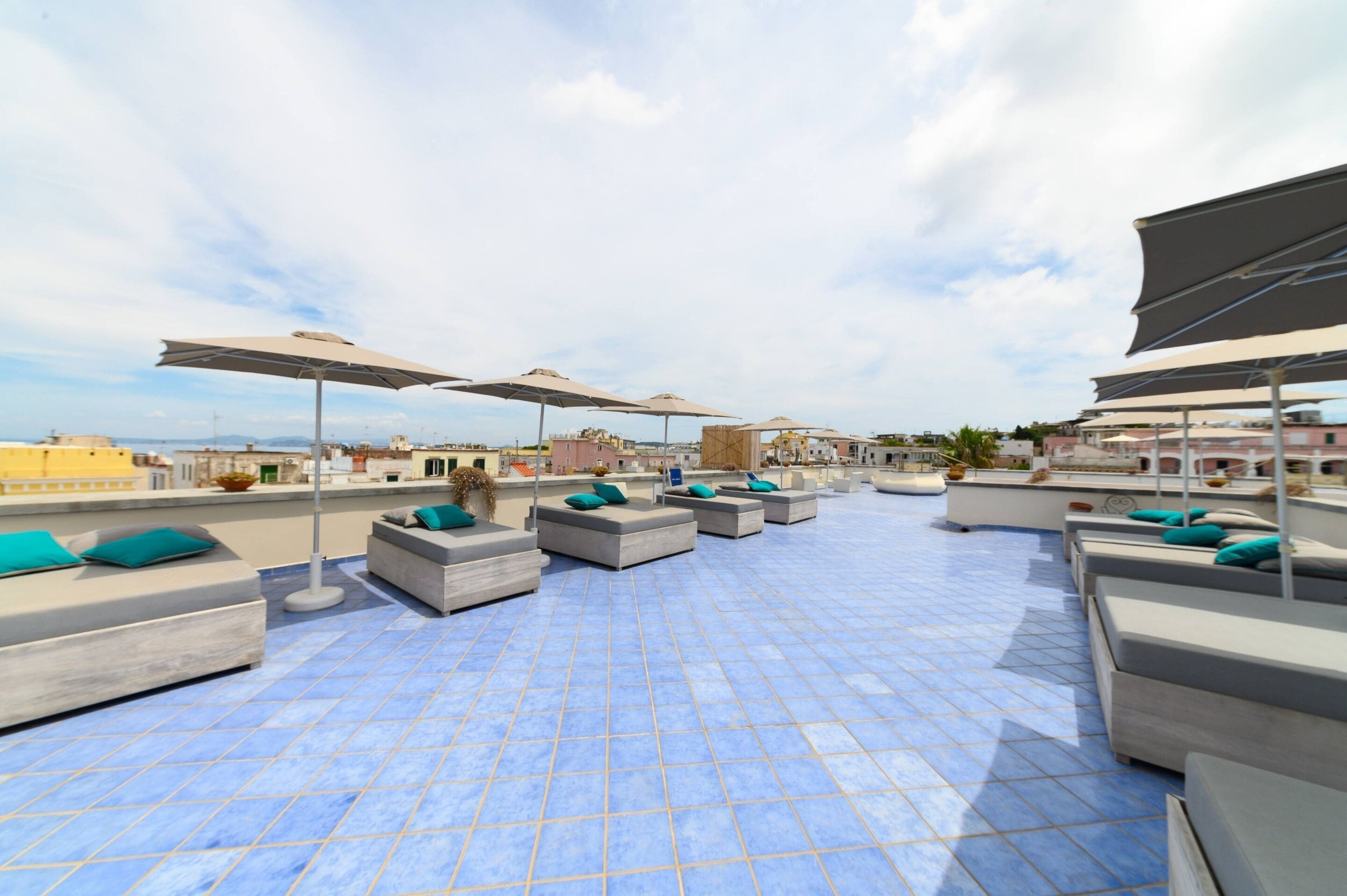 Terraço no telhado com área de estar externa e guarda-sóis, com vista para a paisagem urbana.