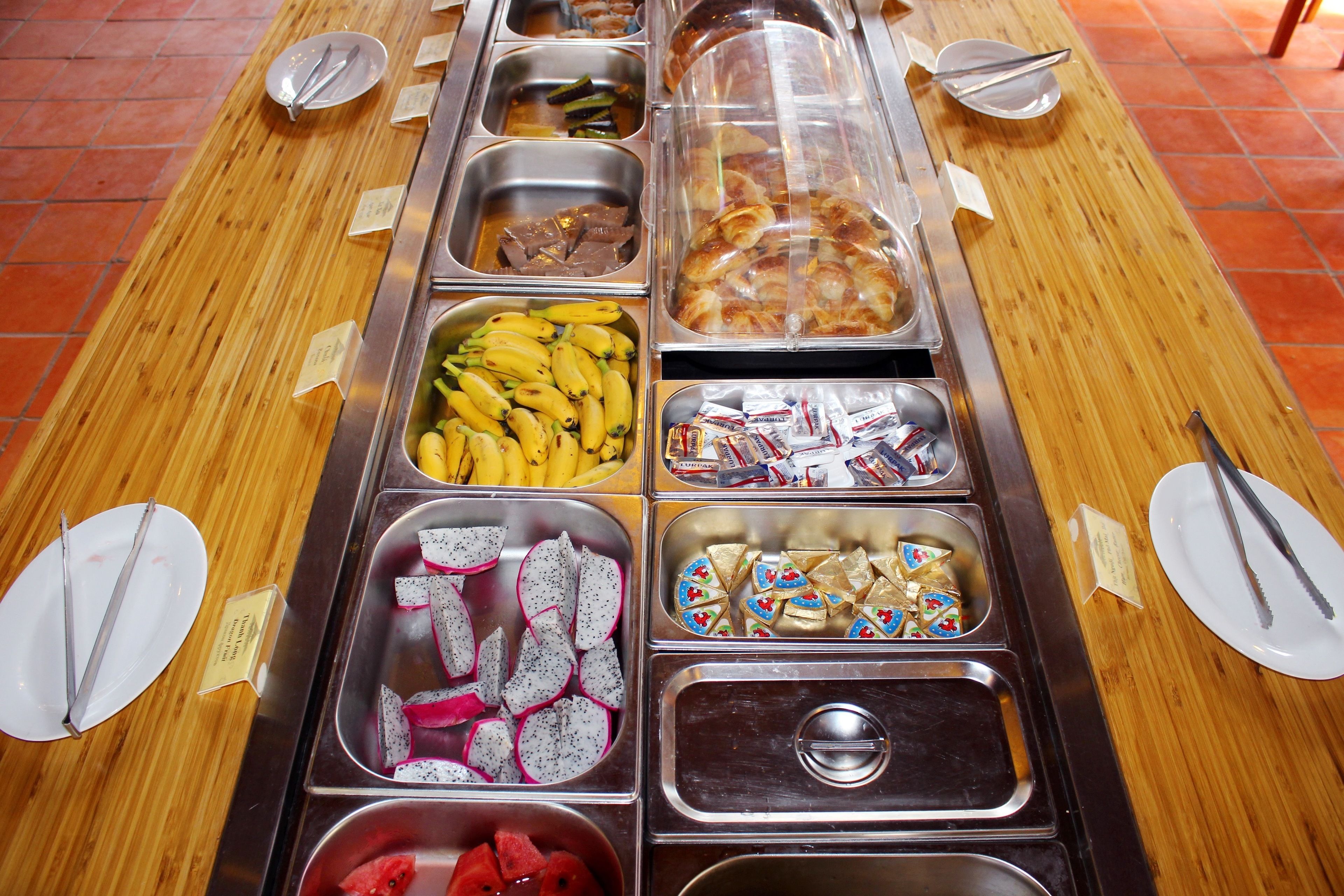 Buffet com diversos alimentos, incluindo frutas, doces e carnes.