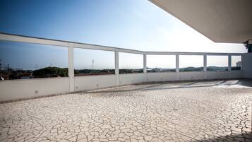 Varanda ampla com piso de azulejos e guarda-corrimão branco, proporcionando vista desobstruída da região.