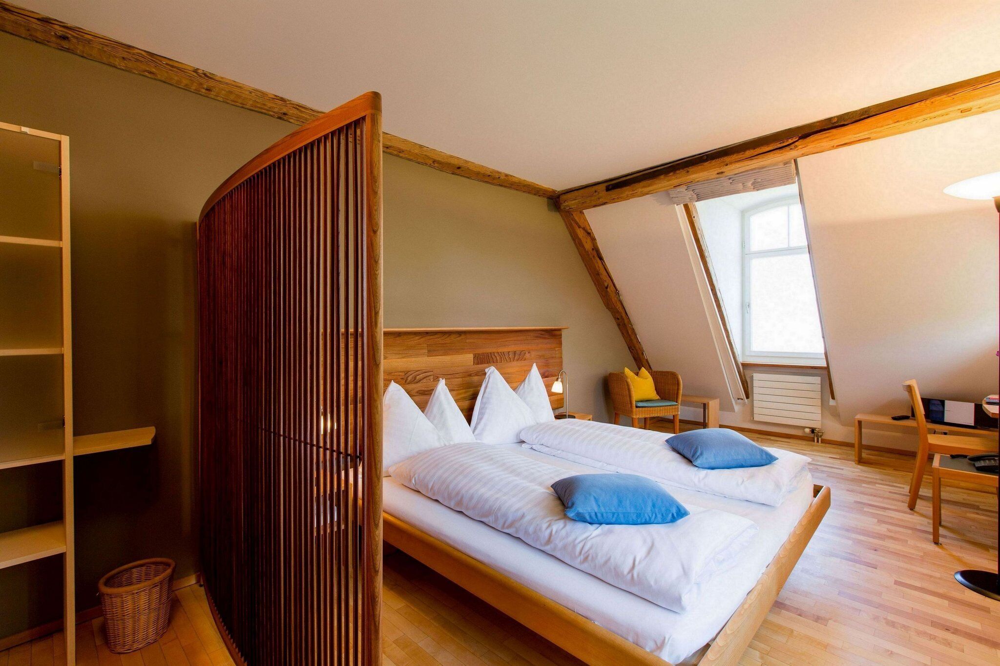 Quarto com duas camas, cabeceira de madeira, escrivaninha e uma cadeira.