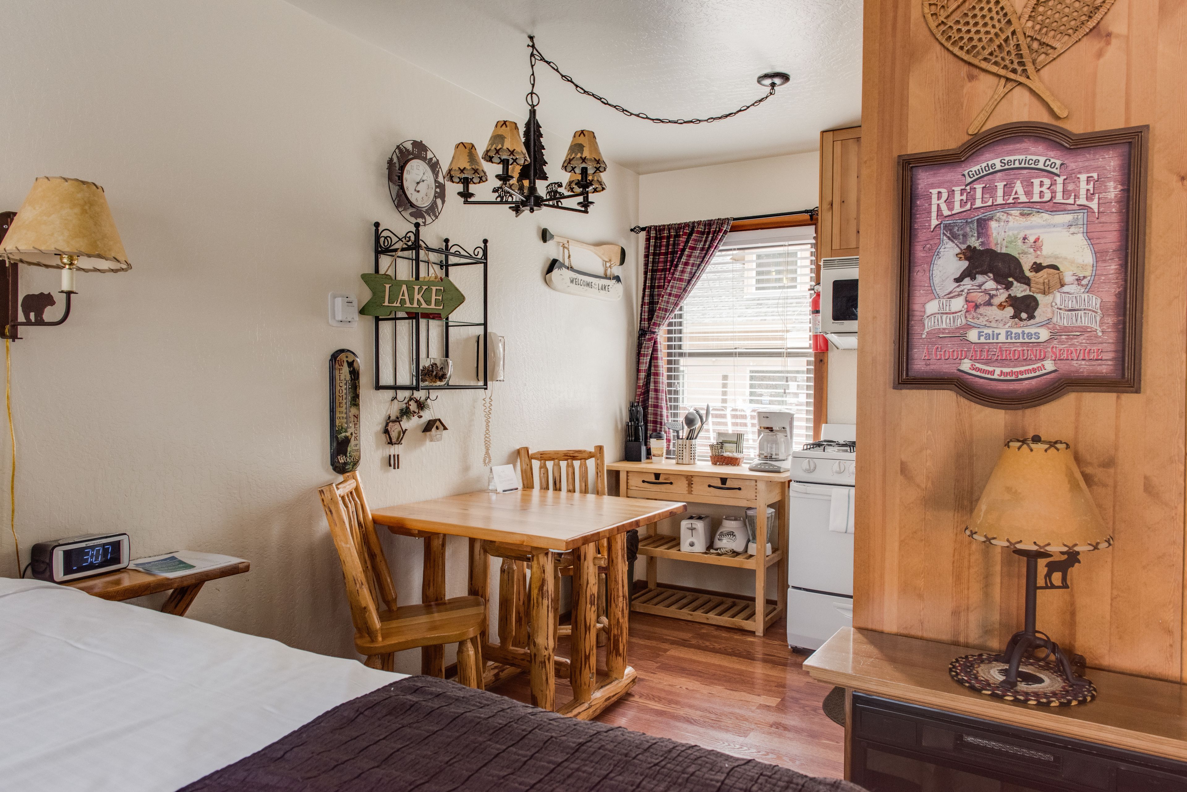 Um quarto aconchegante com uma mesa de jantar de madeira, cadeiras, uma cama e uma escrivaninha com luminária.