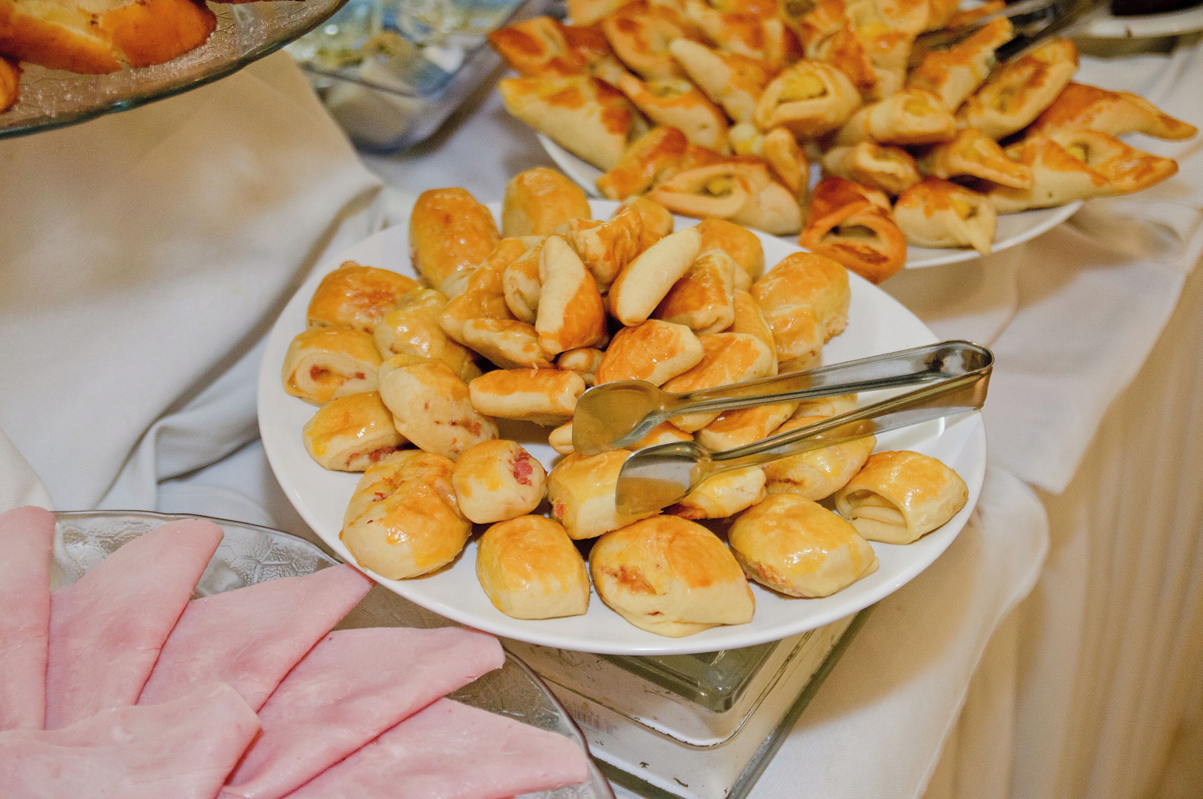 Uma mesa de buffet com diversos alimentos, incluindo doces e fatias de carne.