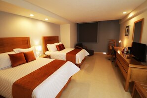 Quarto de hotel com duas camas, uma escrivaninha, uma cadeira e uma televisão.