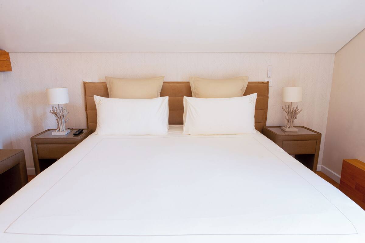 Quarto de hotel com uma cama grande, duas mesas de cabeceira e luminárias.