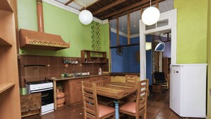 Uma cozinha com mesa e cadeiras de madeira, fogão, pia e geladeira.