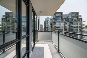 Um apartamento moderno com janelas amplas, varanda e vista para outros edifícios altos.