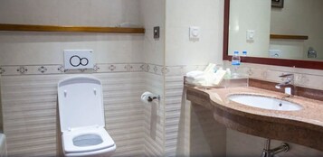 Um banheiro com vaso sanitário, pia e espelho.