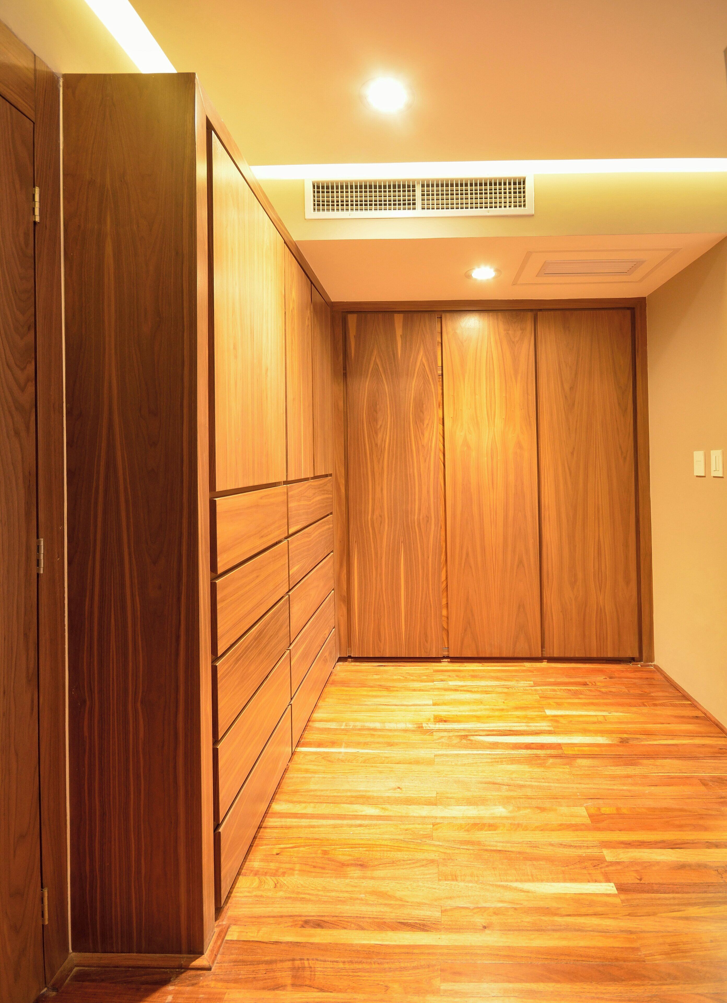 Quarto com soalho de madeira, guarda-roupa grande e ventilação no teto.