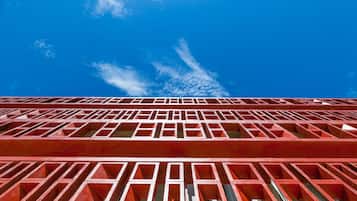 Um edifício vermelho com fachada geométrica e várias aberturas retangulares.