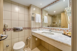 Casa de banho com sanita, duas pias, espelho e porta-toalhas.